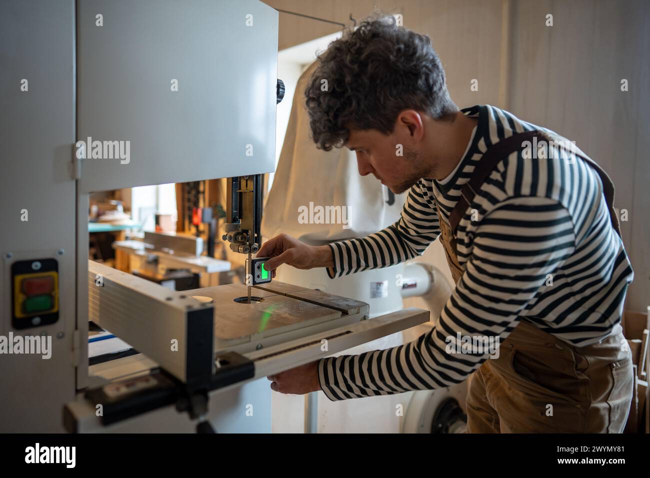 Male carpenter holding digital magnetic inclinometer with level, adjust ...