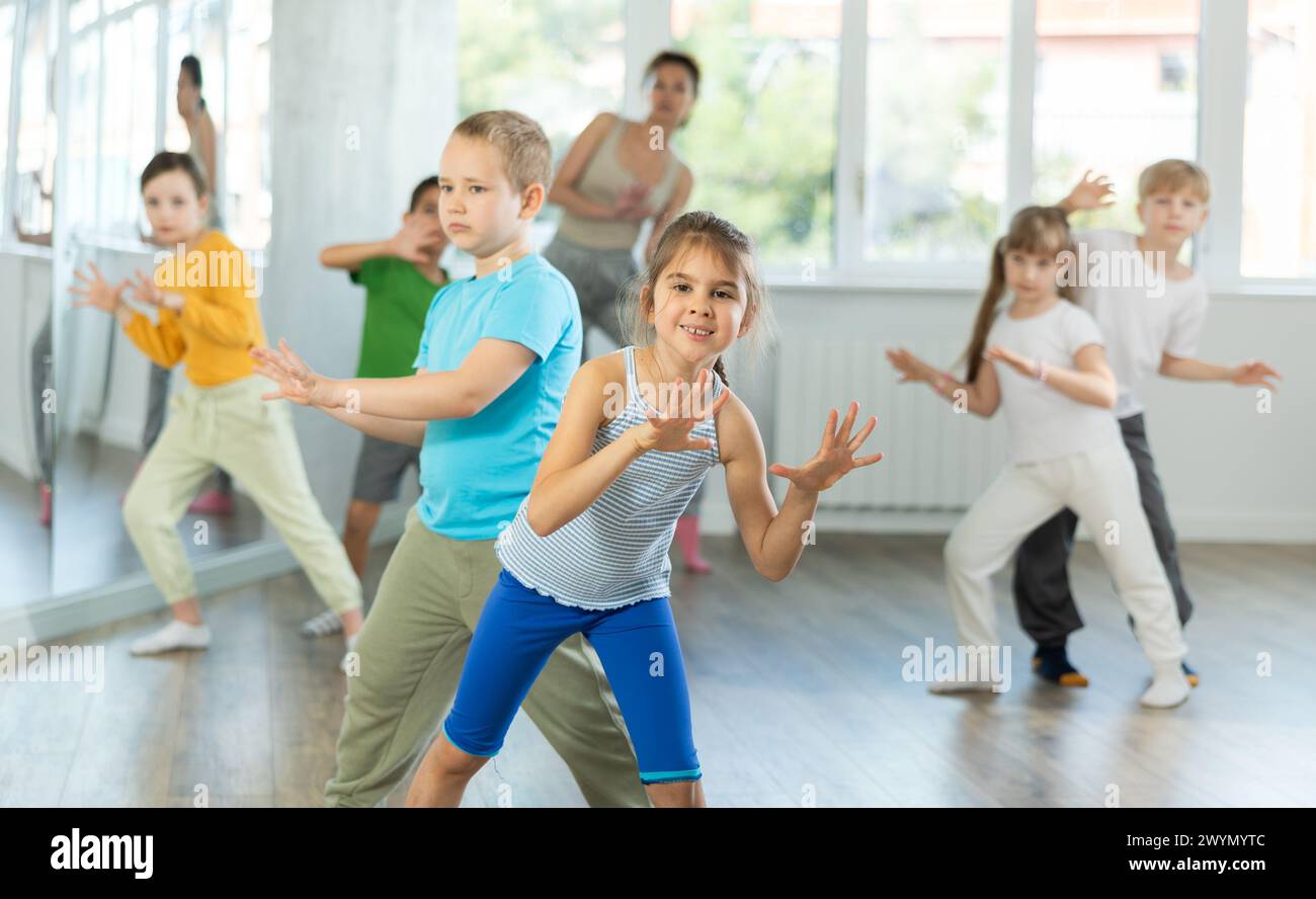 Group of children training movements of twist in dance studio with ...