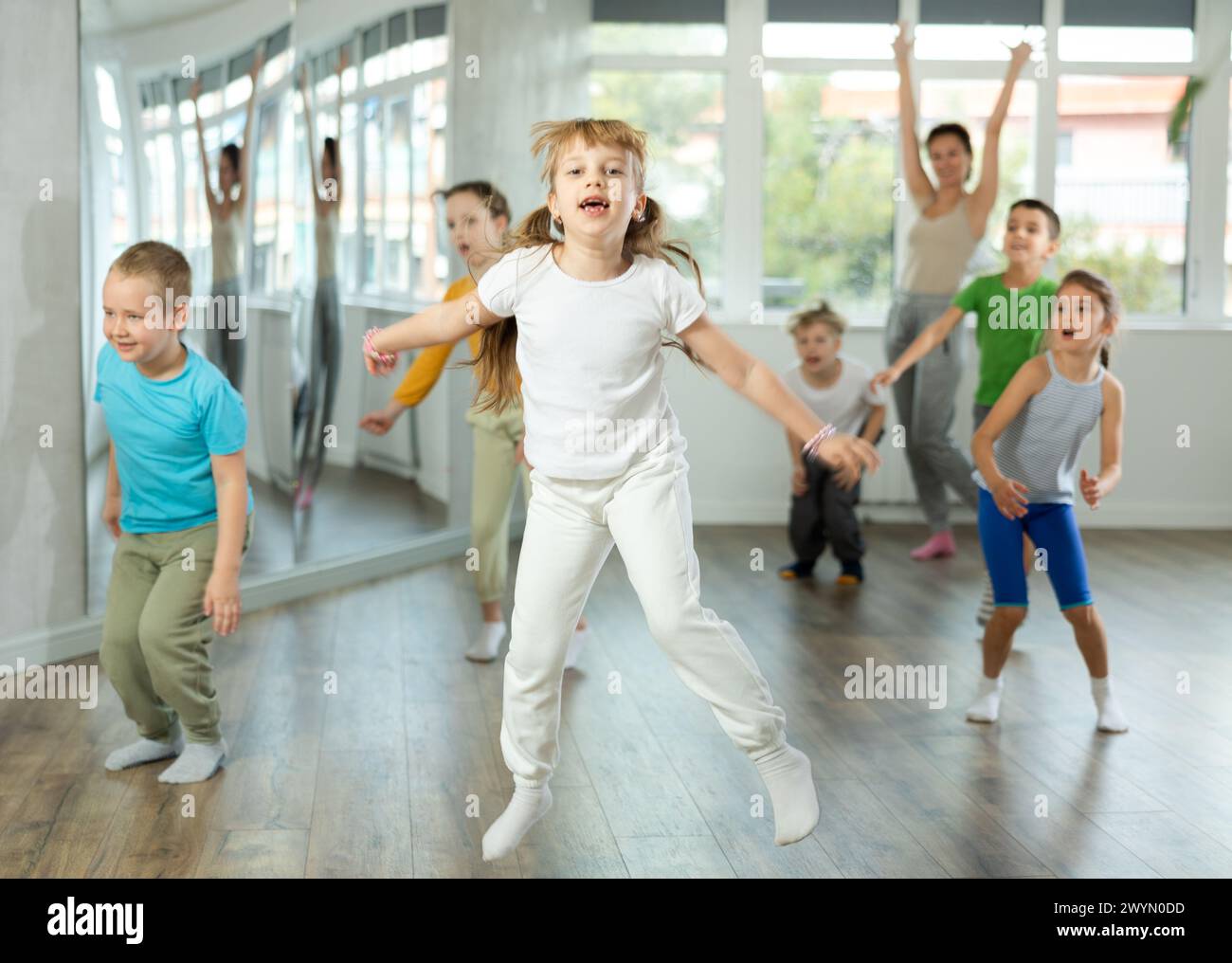 Group of positive juvenile boys and girls jumping cheerfully in ...