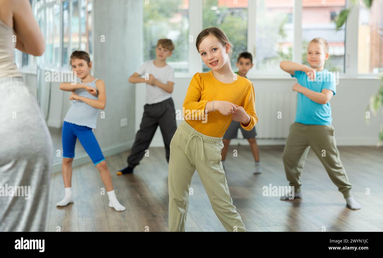 Positive juvenile girl engaged in breakdancing in training room with ...