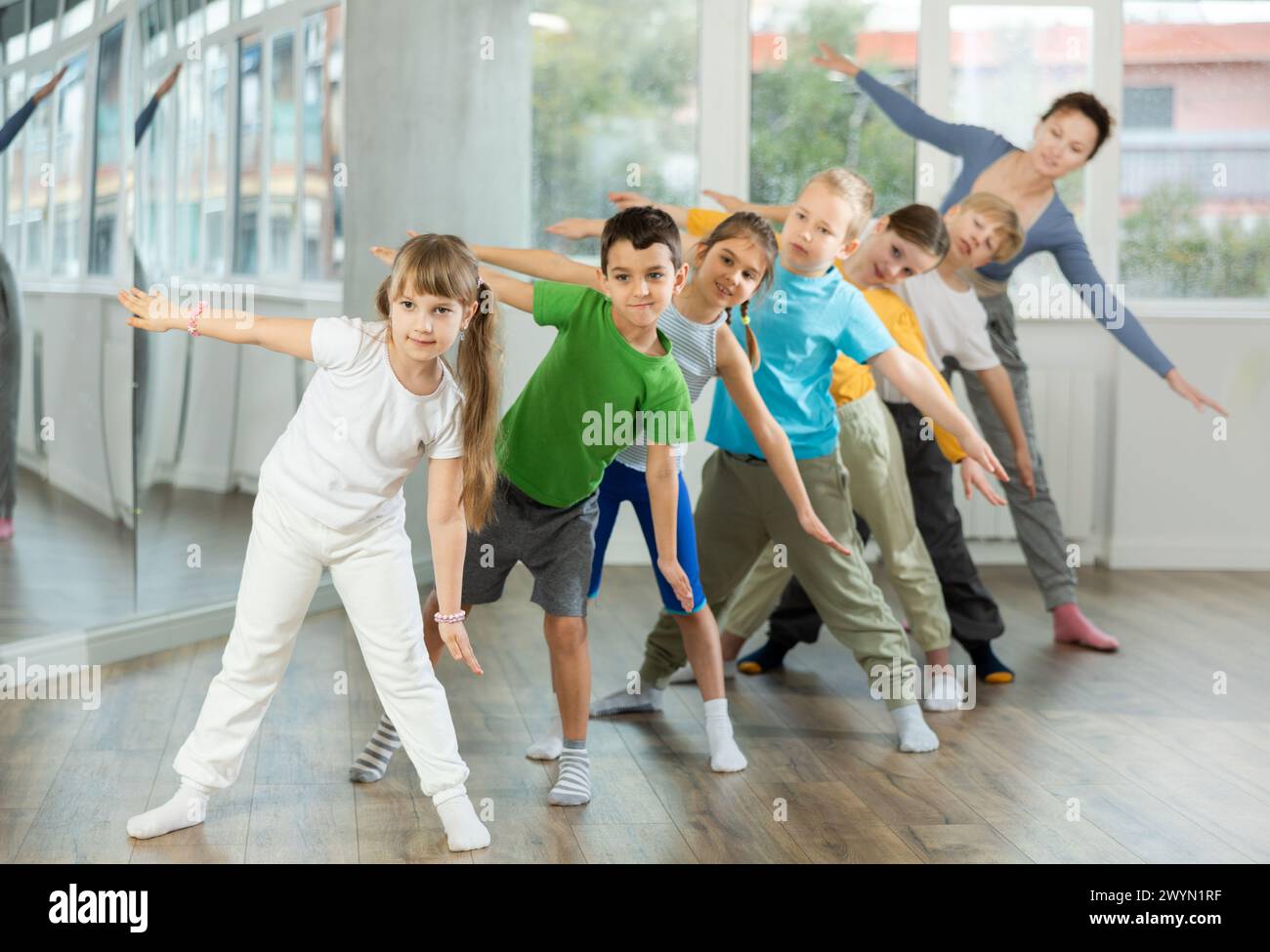Group of tween children standing akimbo in row one by one, learning ...