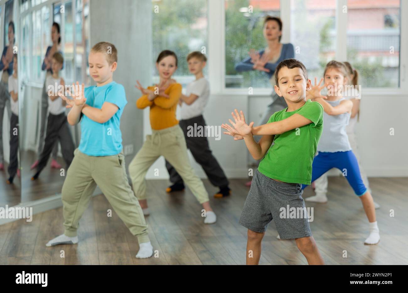 Positive juvenile boy engaged in hip-hop dance in training room with ...