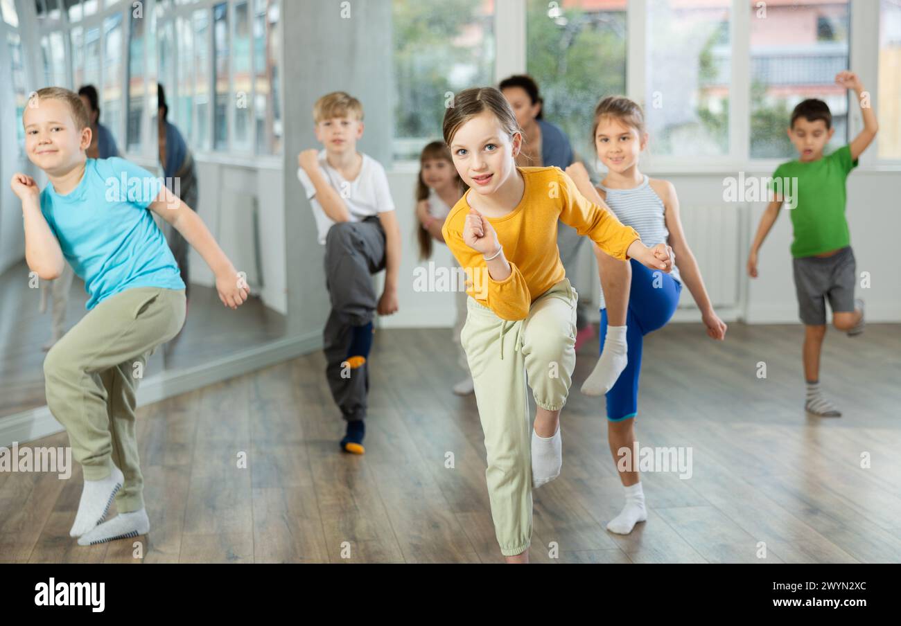 Energetic children practicing modern vigorous movements in dance class ...