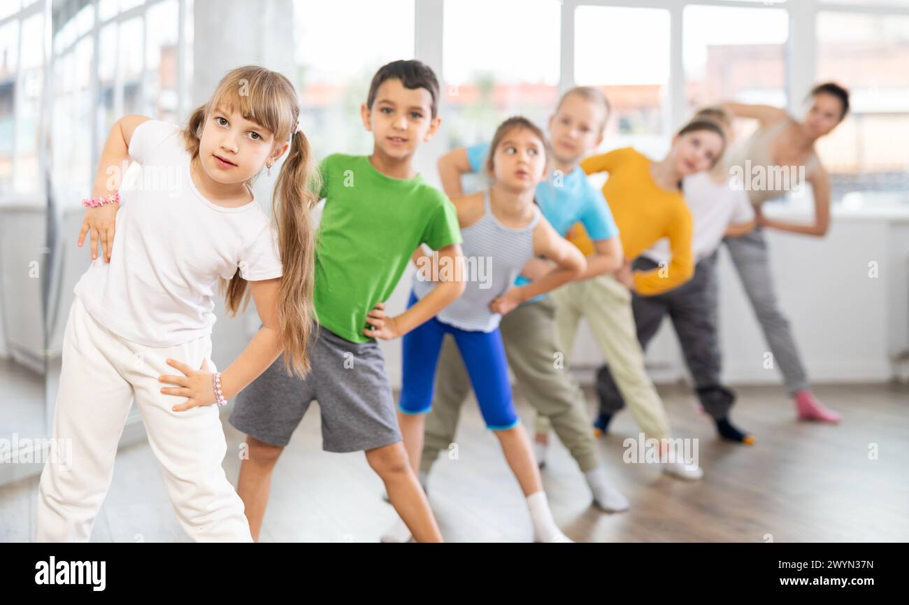 Group of tween children standing akimbo in row one by one, learning ...