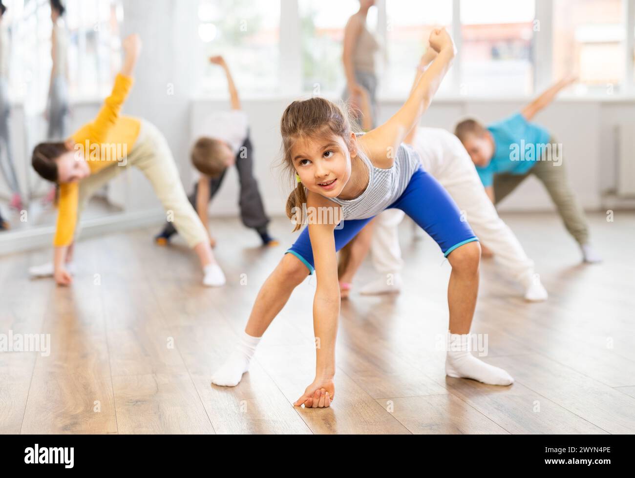 Group of tween children standing akimbo in row one by one, learning ...
