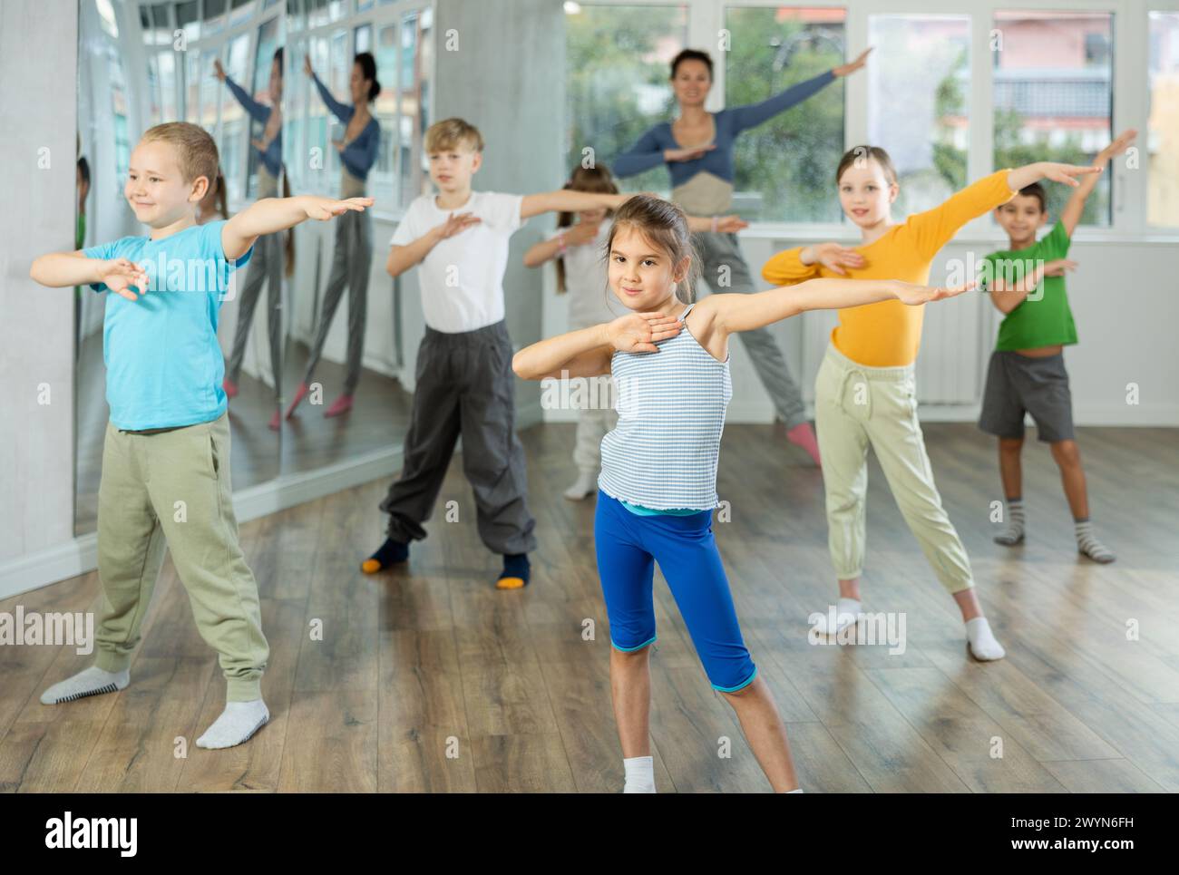 Positive juvenile girl engaged in hip-hop dance in training room with ...