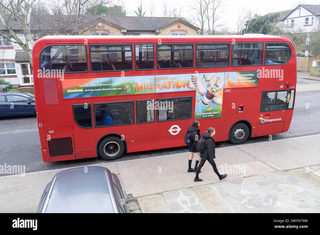two women walk pas on pavement t a huge poster for movie Migration on ...