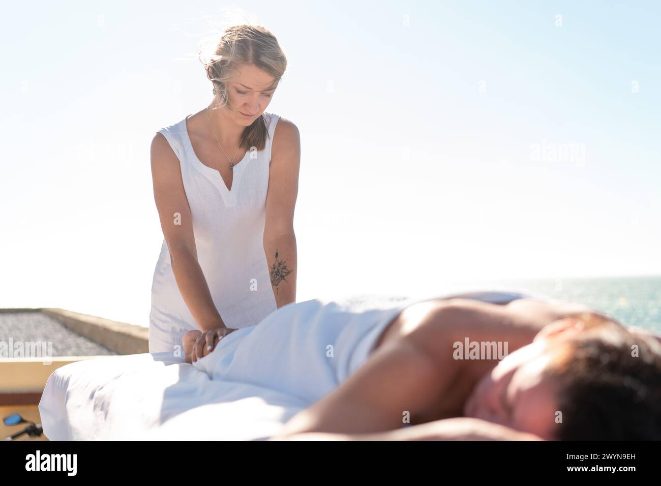 Professional female masseur making massage for brunette woman laying on ...