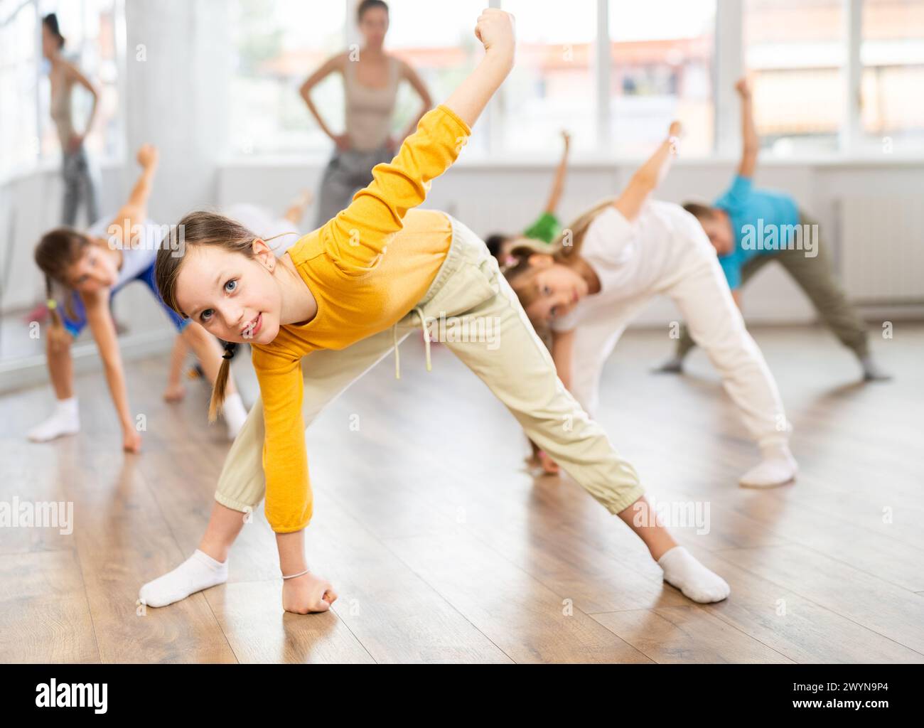 Group of tween children standing akimbo in row one by one, learning ...