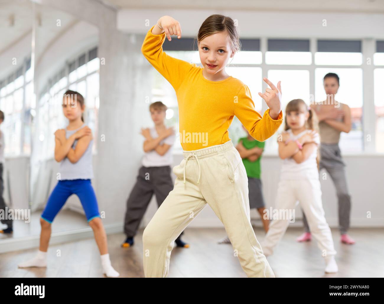 Positive juvenile girl engaged in breakdancing in training room with ...