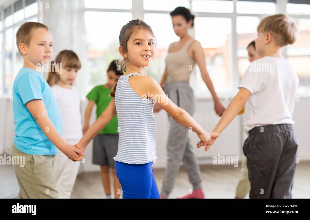 Group of young children dance in ring during dance class with woman ...
