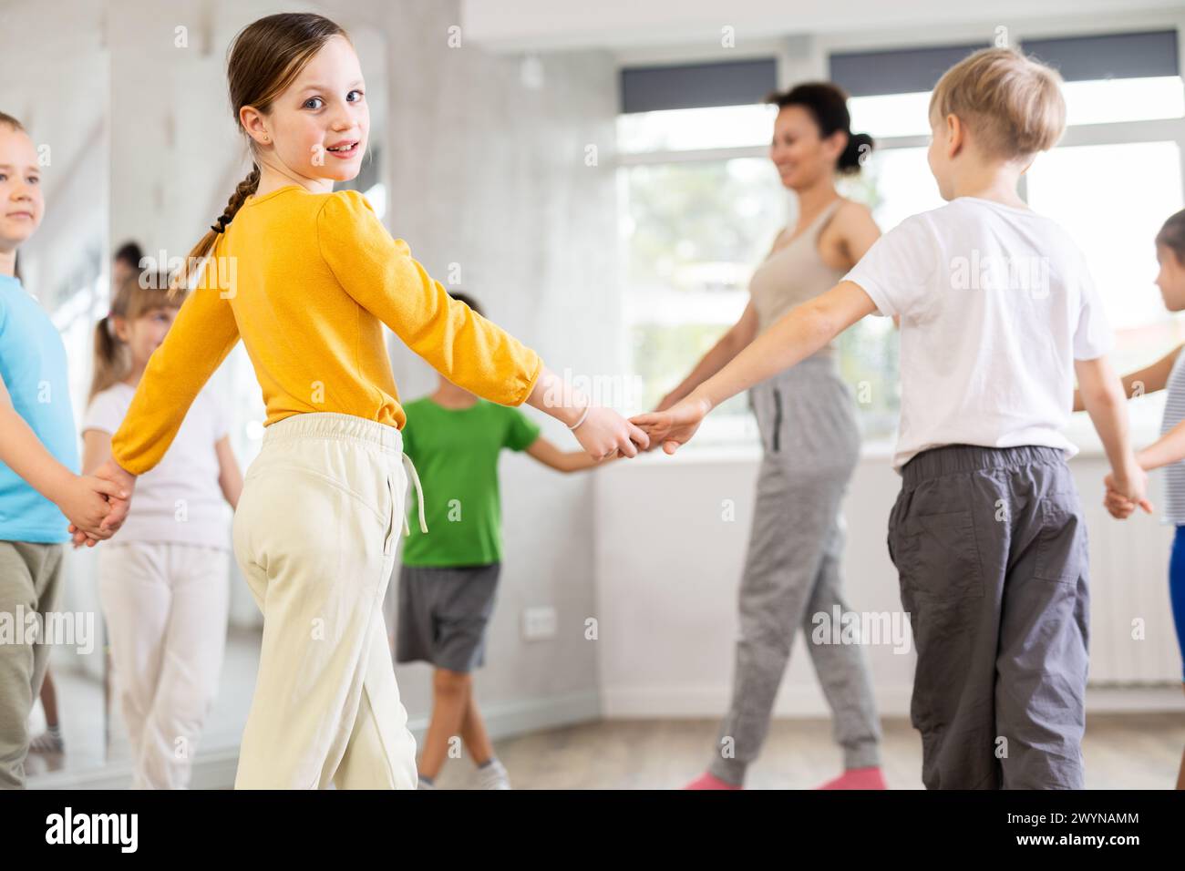 Children holding hands and dancing in round dance in choreography class ...