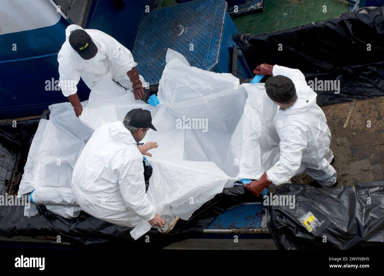 Fishermen wearing protective clothes gathering the fuel spill ...