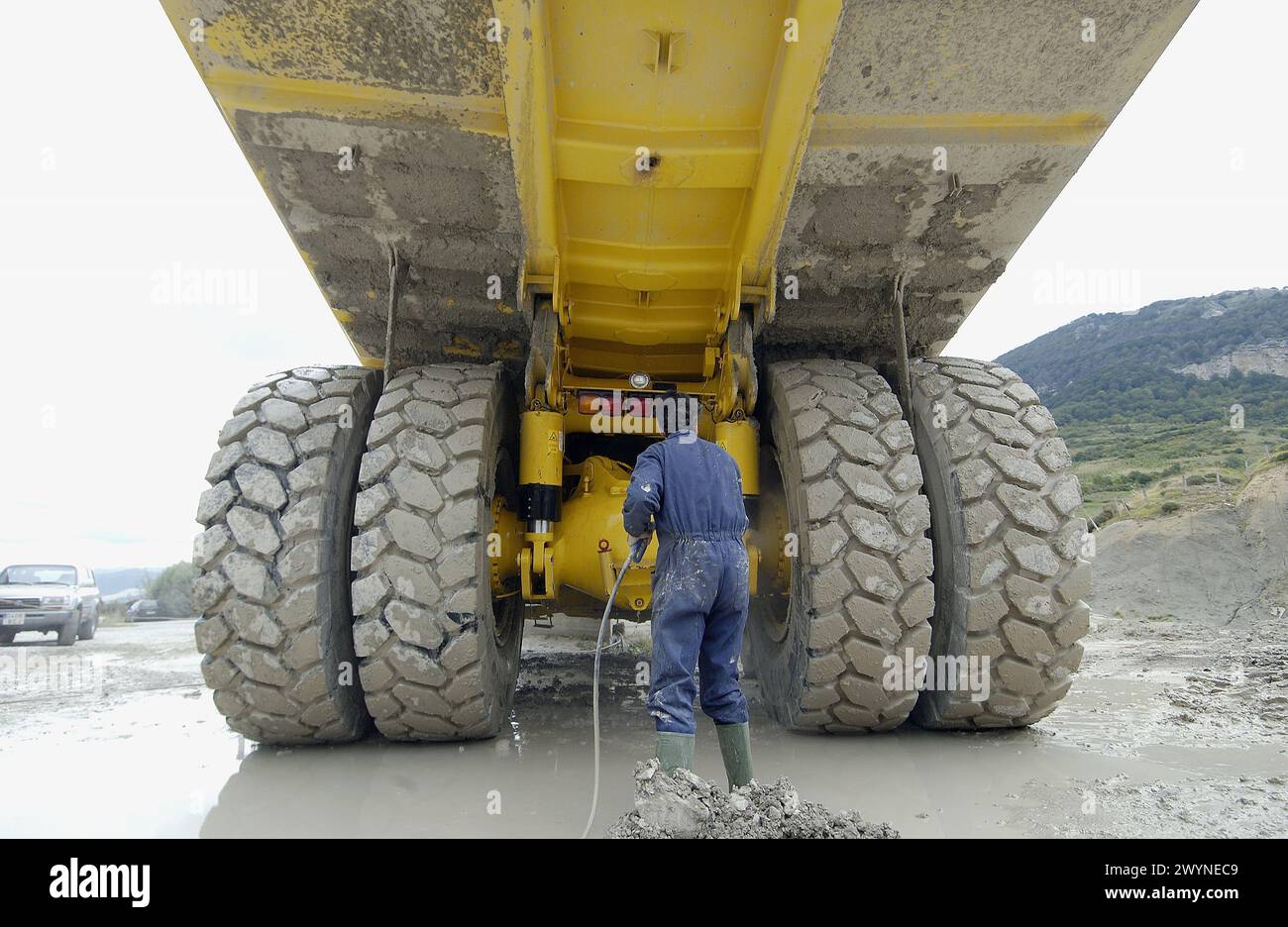 Worker cleaning dumper-truck to carry marl from quarry to cement plant ...