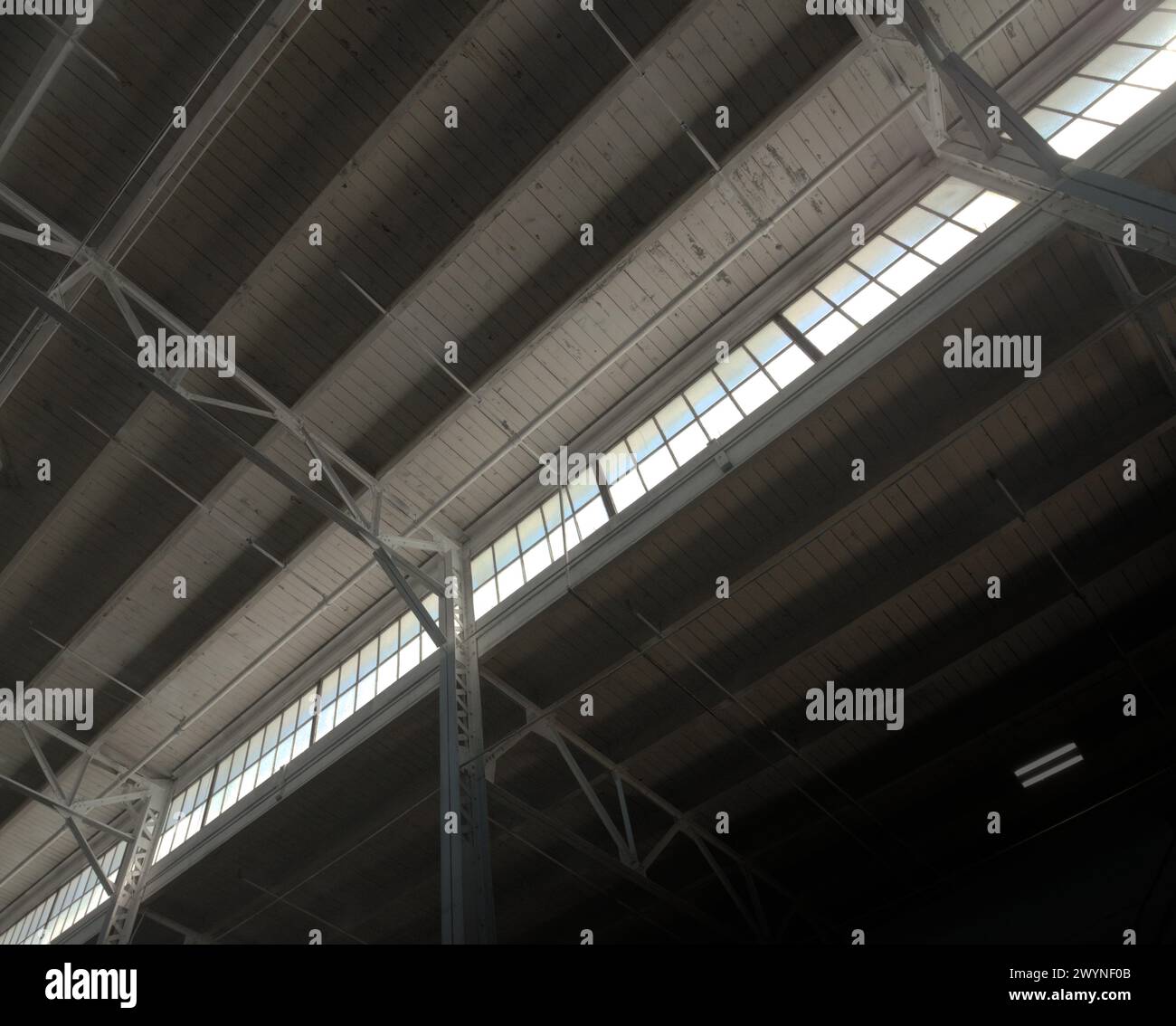 Vast ceiling of a massive industrial warehouse illuminated by rows of ...