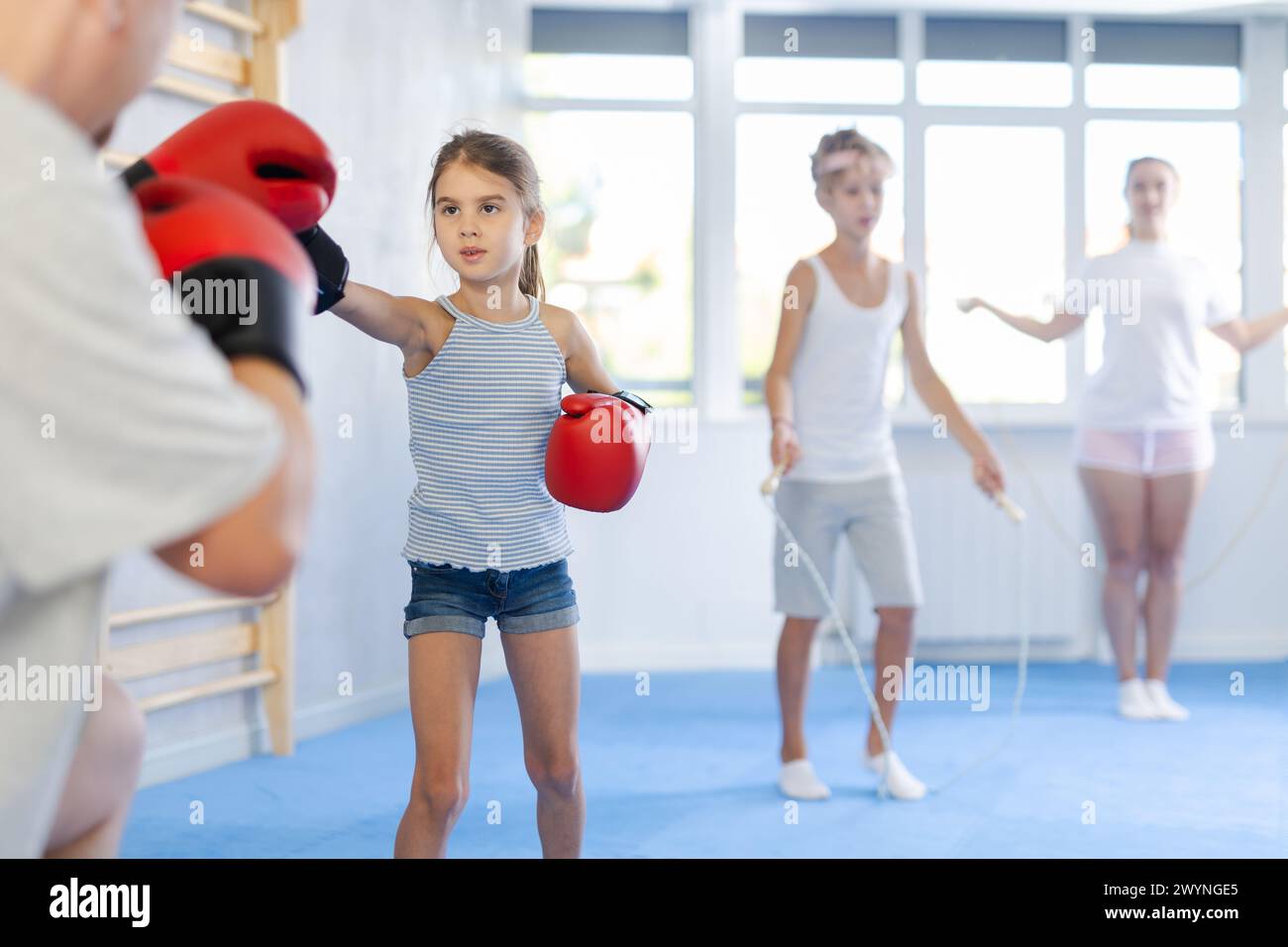 Girl and dad are boxing in gym, father helps child to work out force of ...