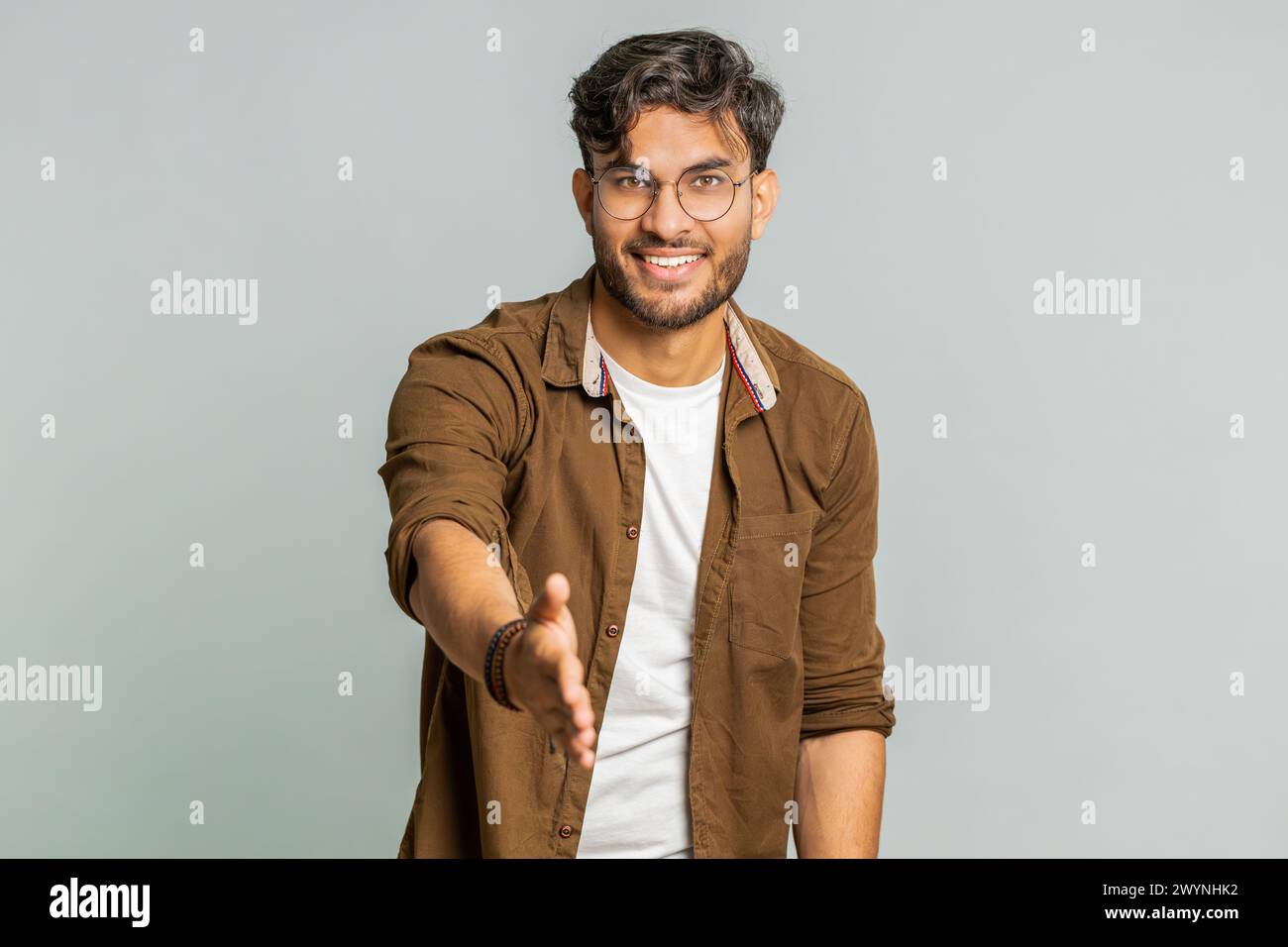 Friendly Indian young man outstretching hand to camera, offering ...