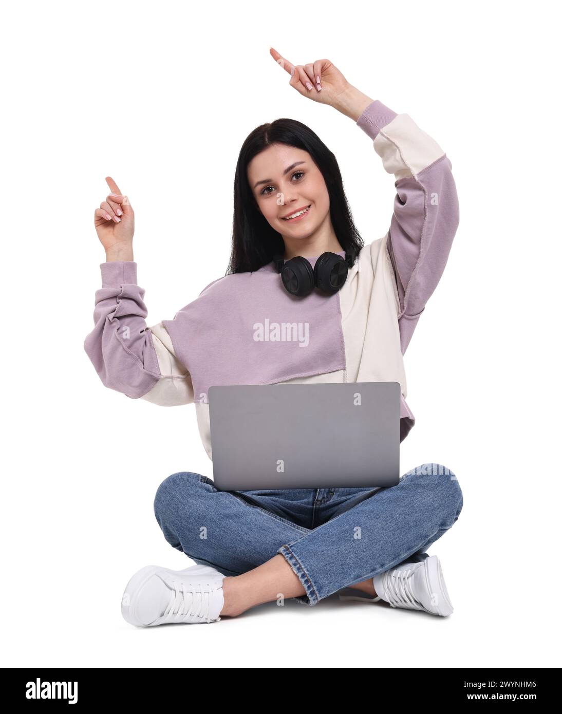 Smiling student with laptop pointing at something on white background ...