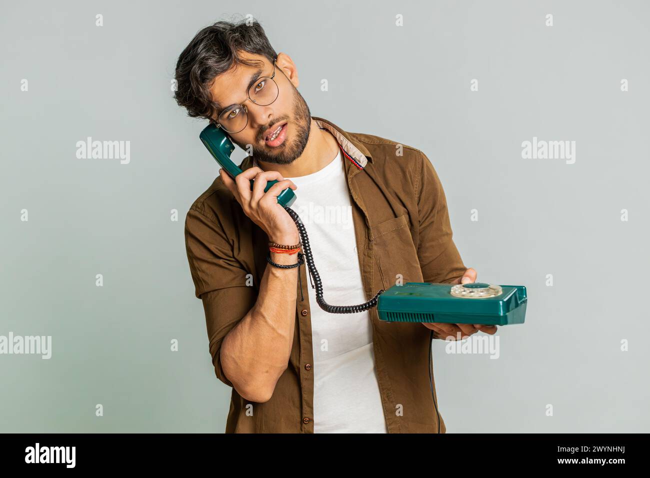 Tired bored Indian man talking on wired vintage telephone of 80s ...
