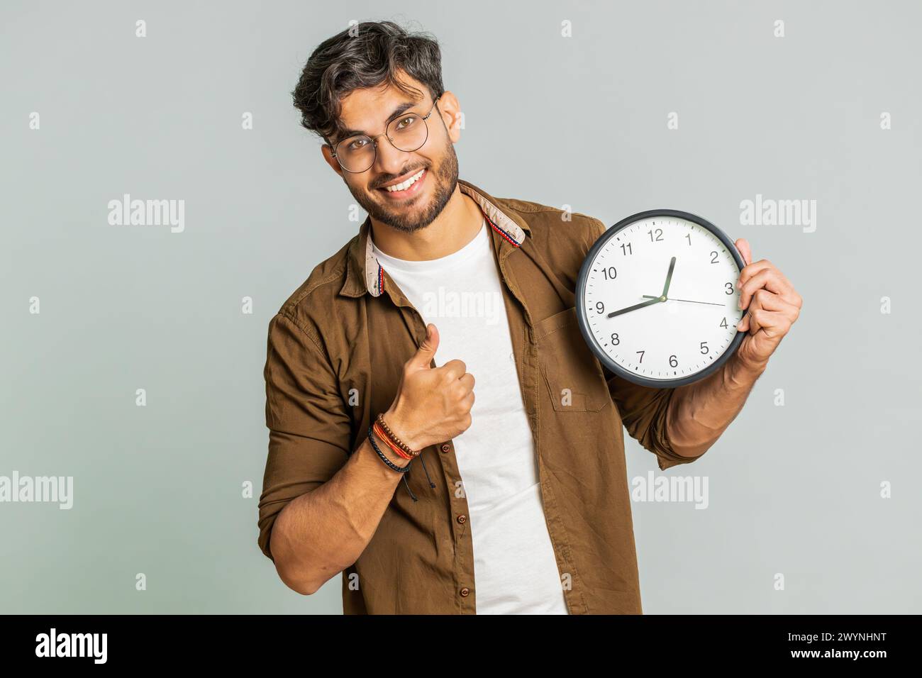 It is your time, hurry up. Indian young man showing time on wall office ...