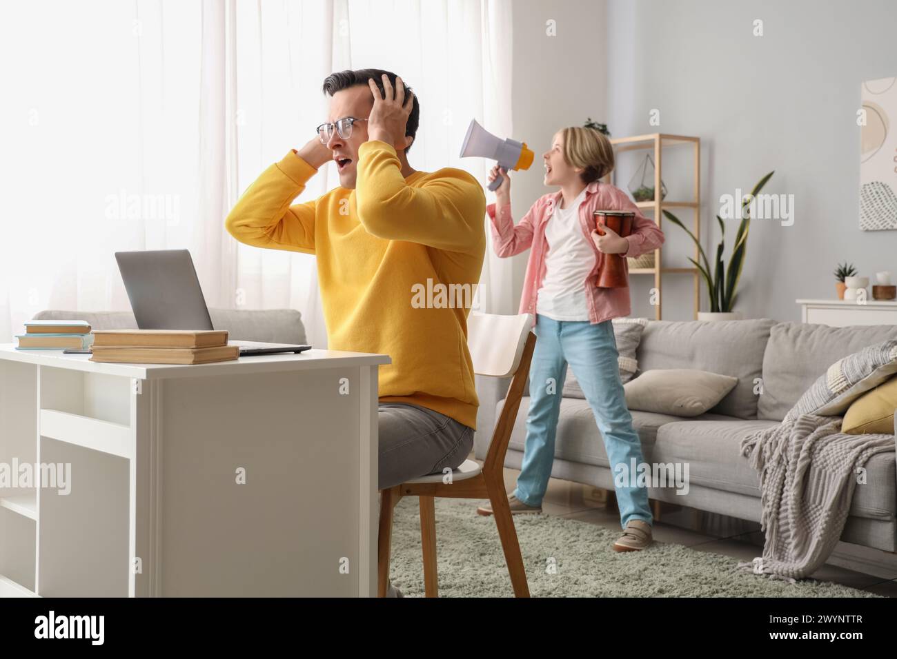 Working young man stressed of his noisy little son at home Stock Photo ...