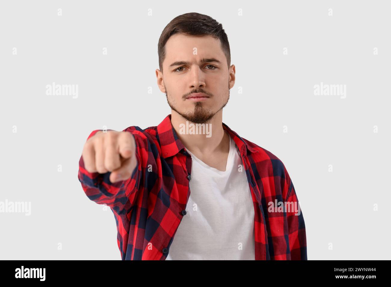 Young man pointing at viewer on white background, closeup. Accusation ...