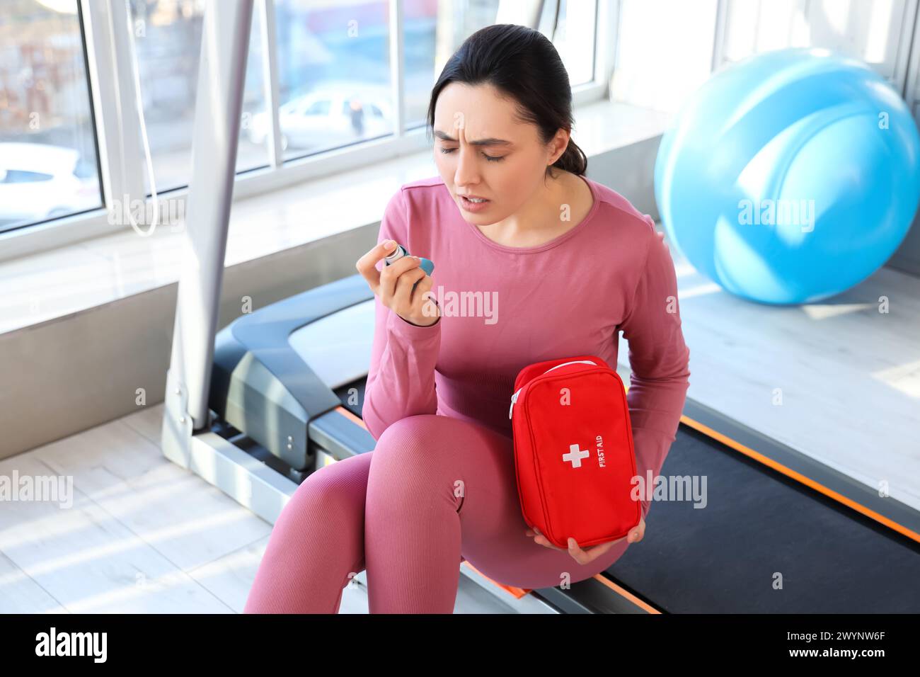 Sporty young woman with inhaler and first aid kit having asthma attack ...