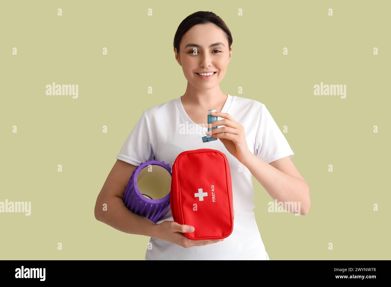 Sporty young woman with inhaler, first aid kit and foam roller on green ...