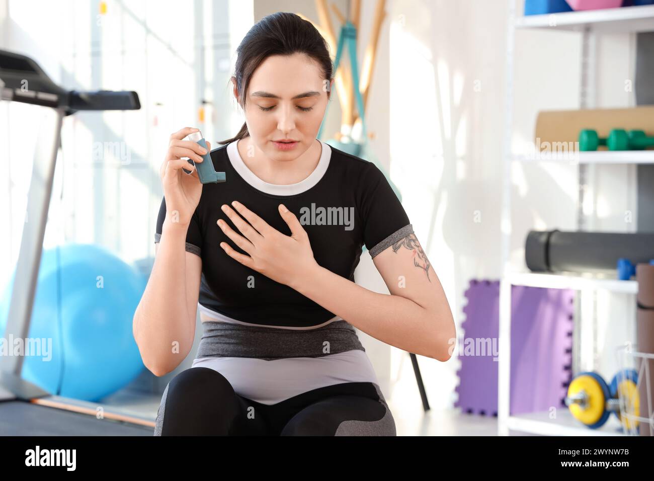 Sporty young woman with inhaler having asthma attack in gym Stock Photo ...