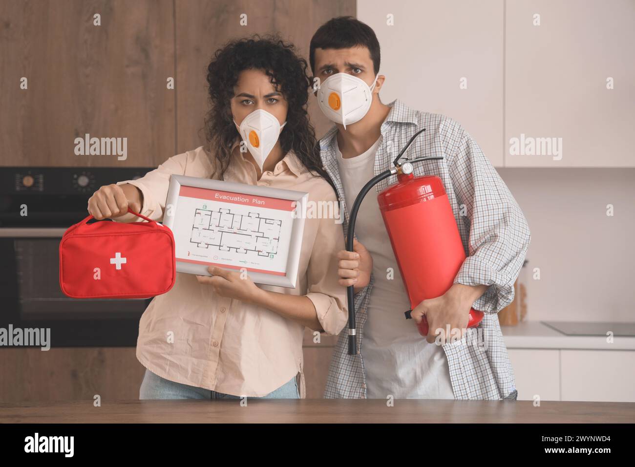 Young couple with evacuation plan, first aid kit and fire extinguisher in burning kitchen Stock ...