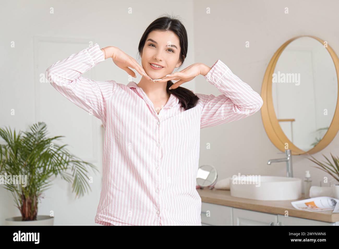 Beautiful young happy woman after face building exercise in bathroom ...