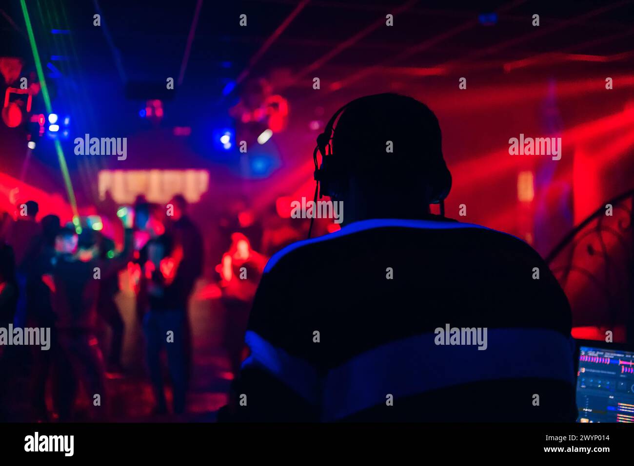 DJ mixes music in a nightclub with people dancing on the dance floor ...