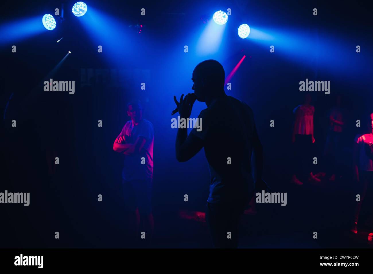 mc with microphone on the night club scene on the background of blurred ...