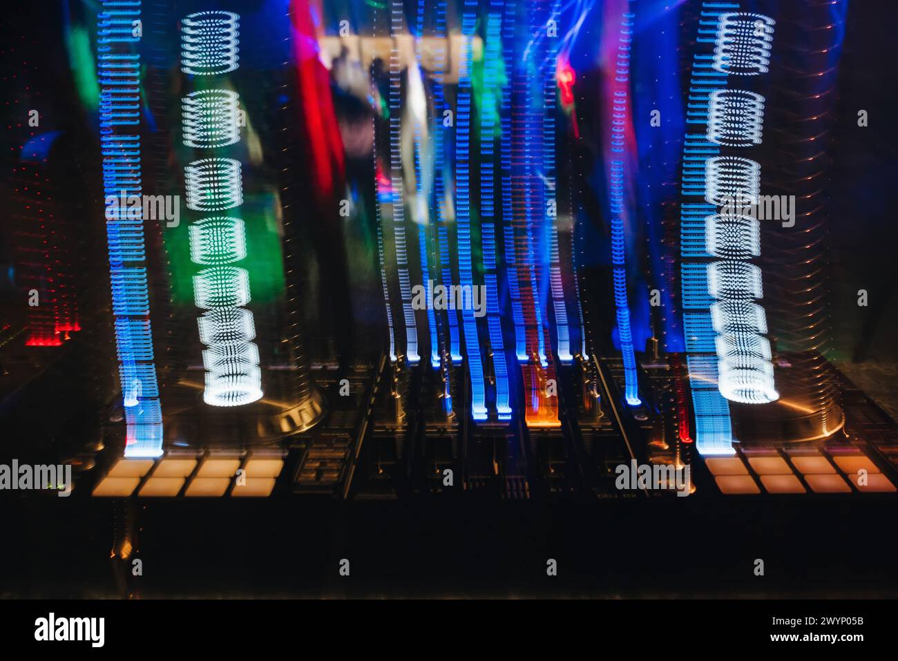 DJ mixer in a nightclub with glowing colored lights from controllers ...