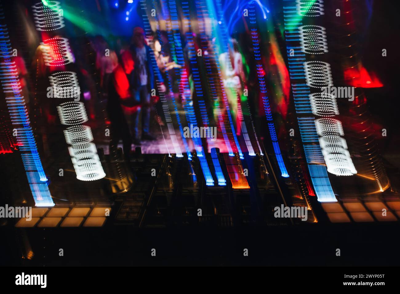 DJ mixer in a nightclub with glowing colored lights from controllers ...