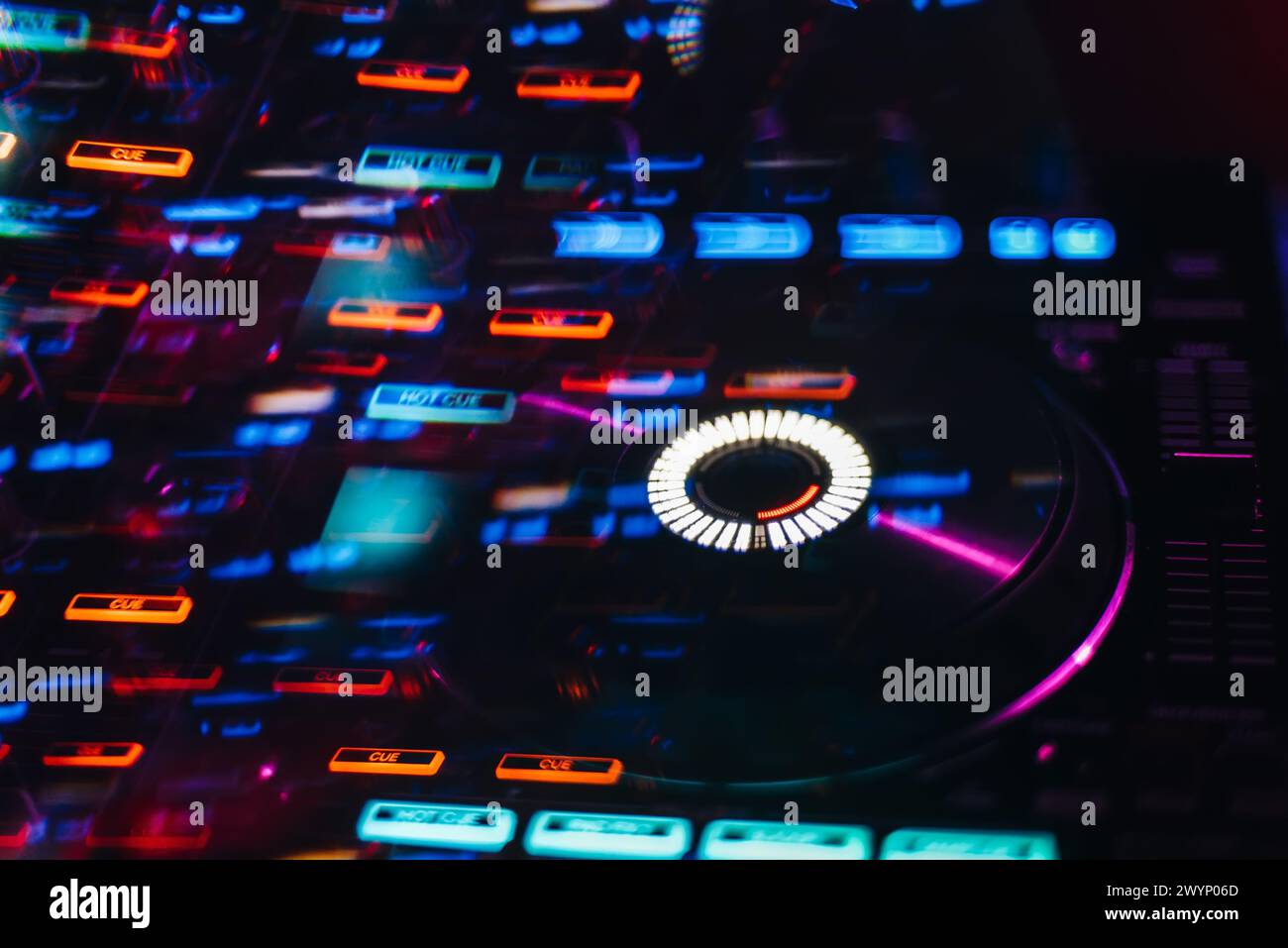 DJ mixer in a nightclub with glowing colored lights from controllers ...