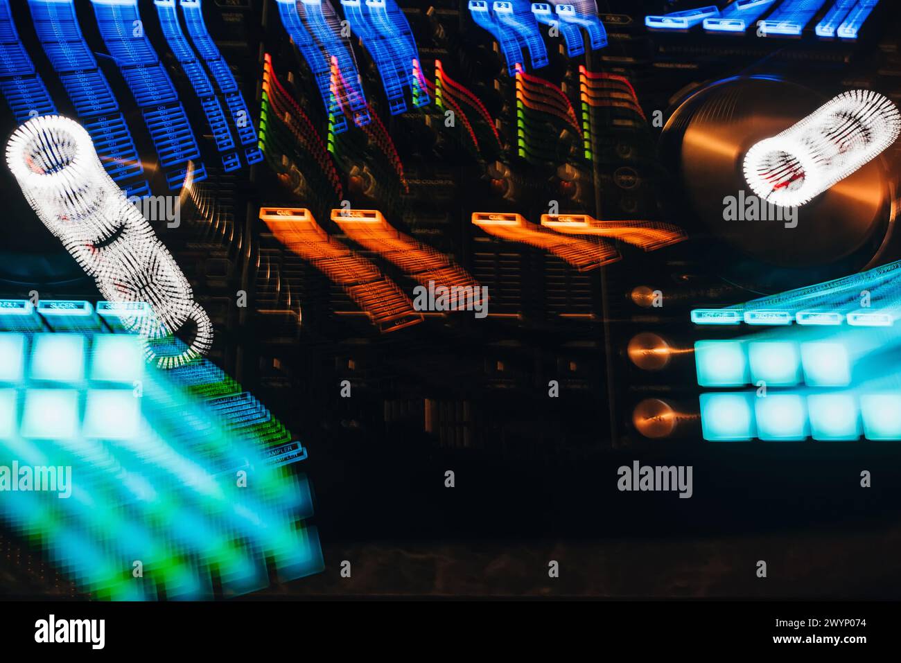 DJ mixer in a nightclub with glowing colored lights from controllers ...
