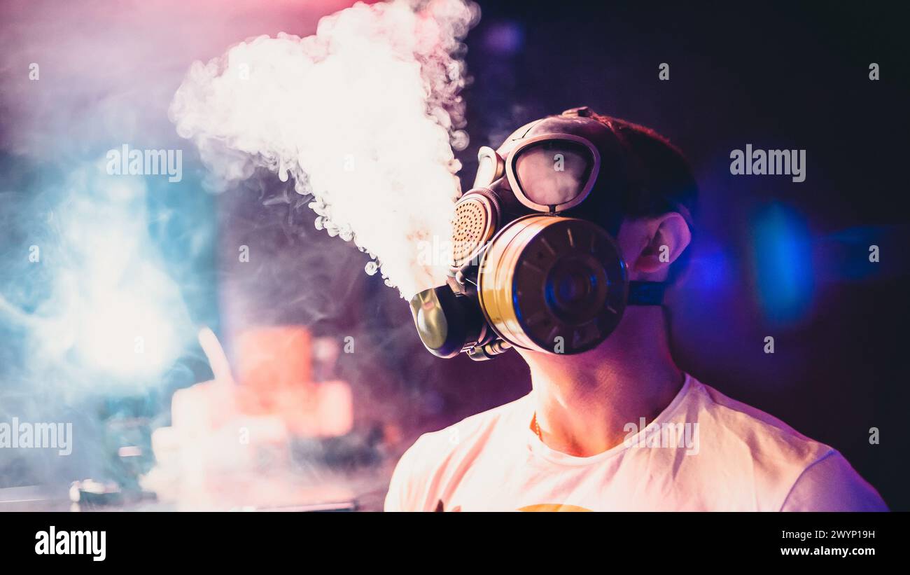 man lets clouds of hookah smoke in a gas mask. Soft focus and grain ...