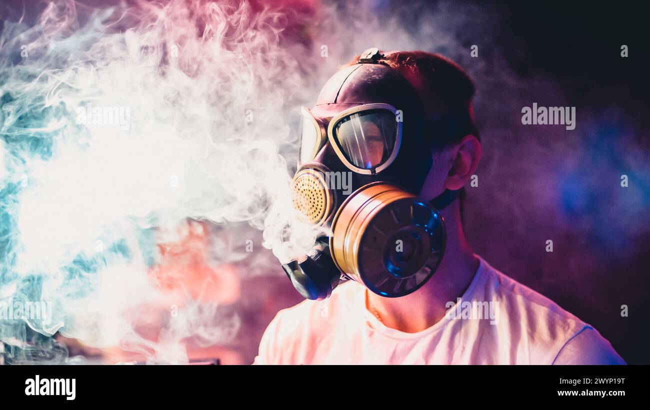 man in a gas mask smokes a hookah and breathes a cloud of tobacco smoke ...