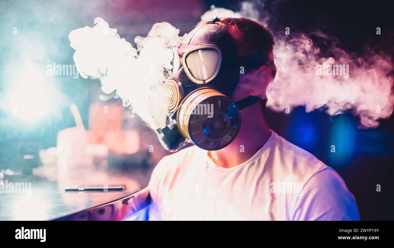 man in a gas mask smokes a hookah and breathes a cloud of tobacco smoke ...