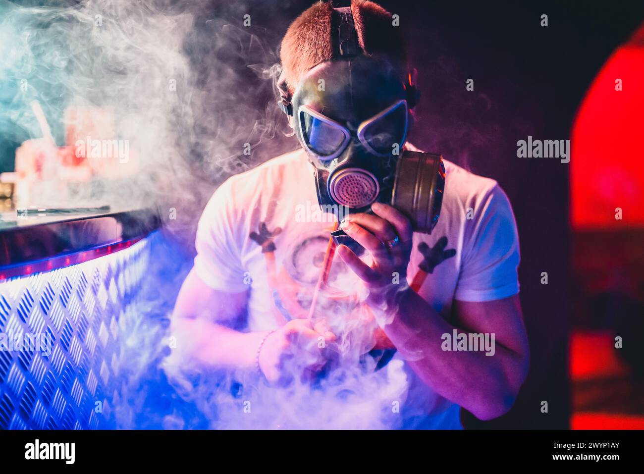 man in a gas mask Smoking a hookah and blowing smoke. Soft focus and ...