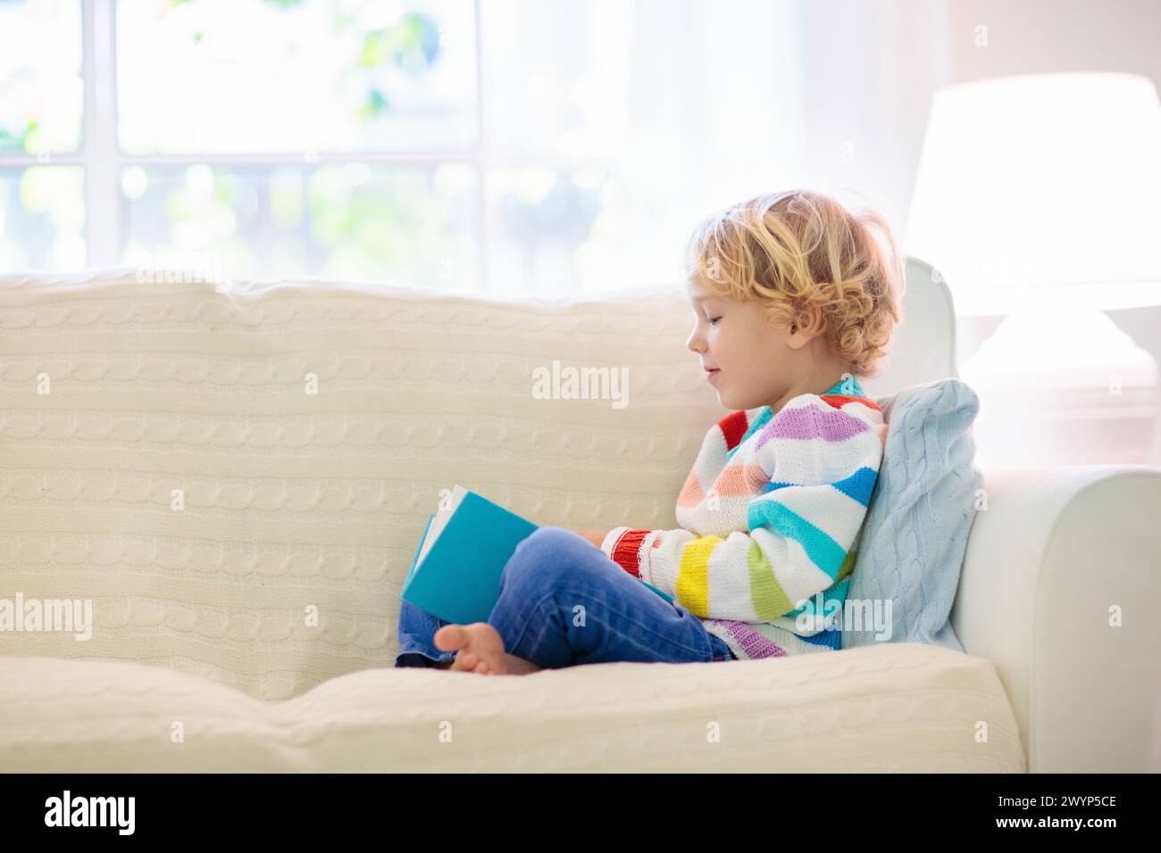 Child reading book. Kids read books. Little boy sitting on white couch ...