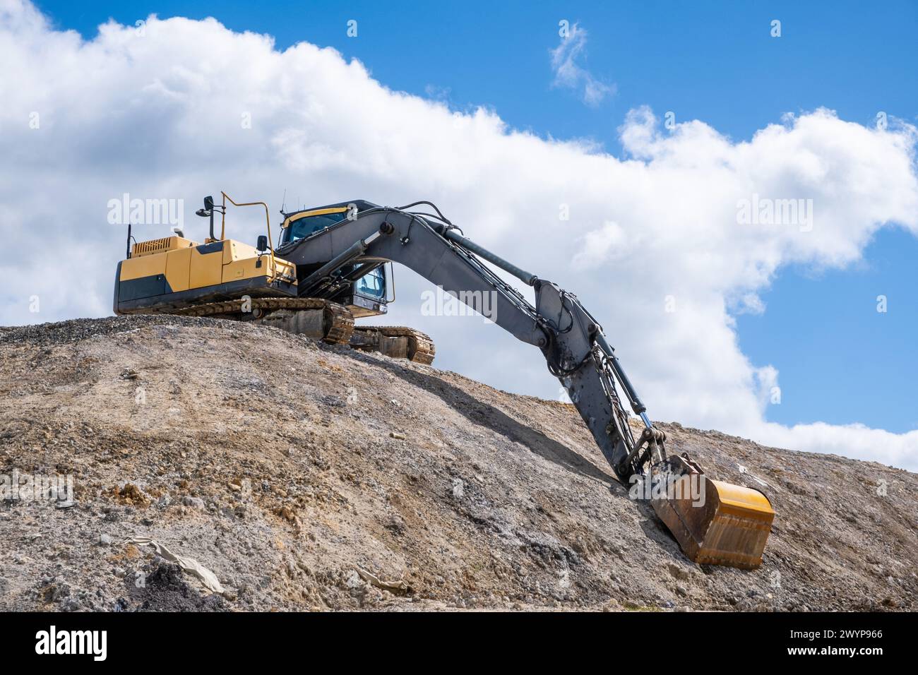 Excavator with arm outstretched straightening an earth embankment Stock ...