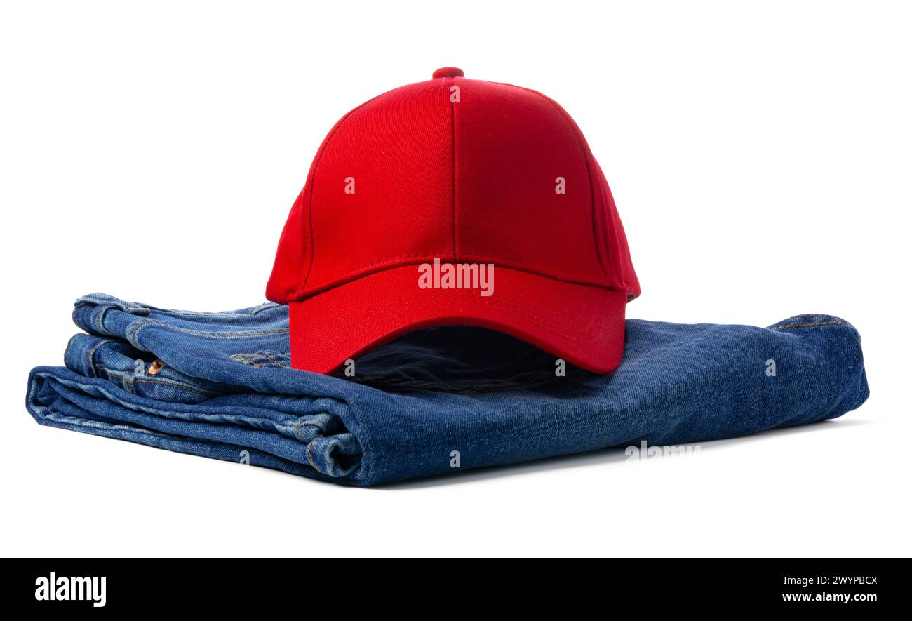 Red Baseball Cap Resting Atop Folded Blue Denim Jeans Against a White ...