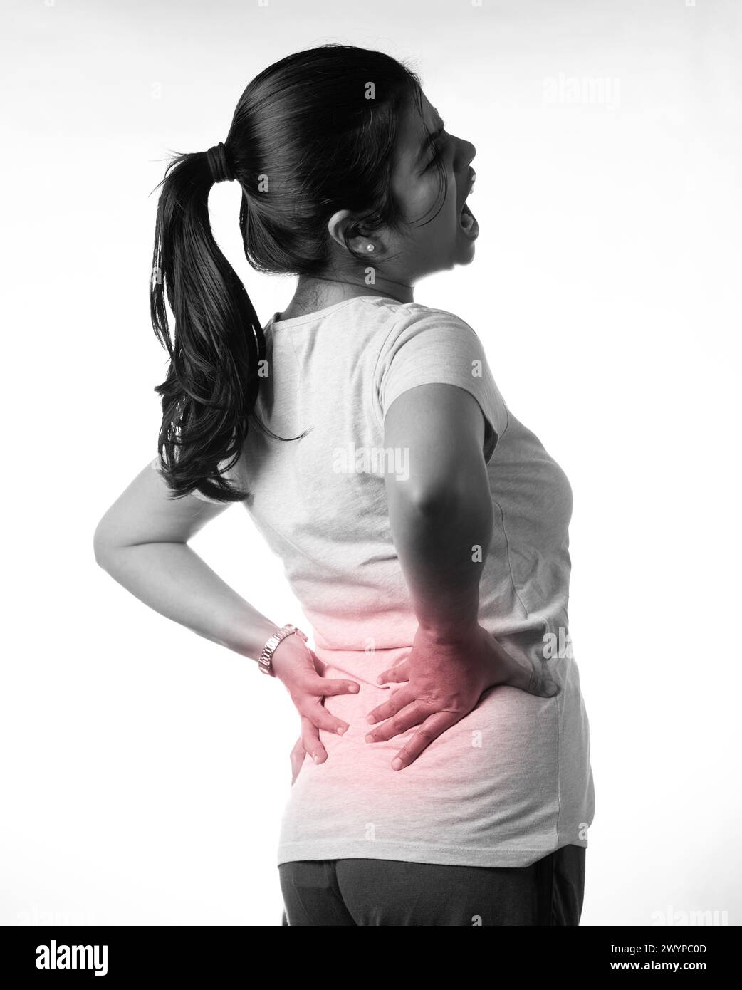 An Indian woman holding her back for pain showing painful expression on ...