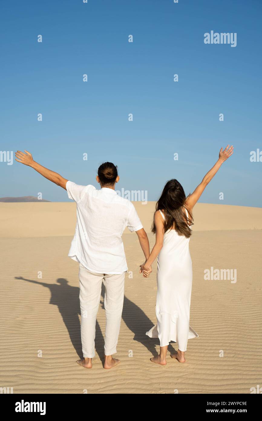 Vertical view of young man and woman holding hands backwards and ...