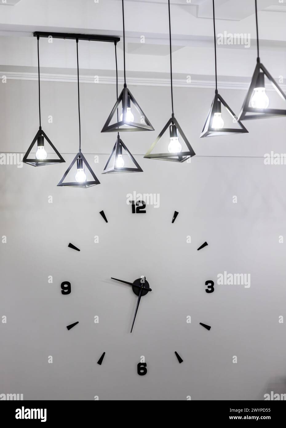 Minimalistic design of a wall clock with black numbers and a light bulb ...