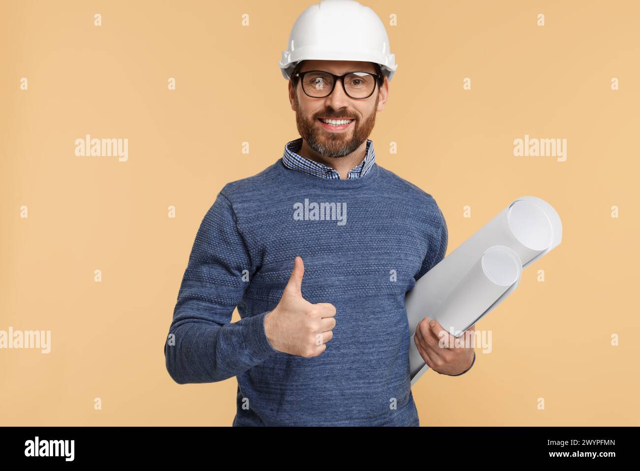 Architect in hard hat with drafts showing thumbs up on beige background ...