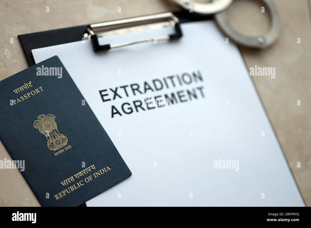 Passport of India and Extradition Agreement with handcuffs on table ...