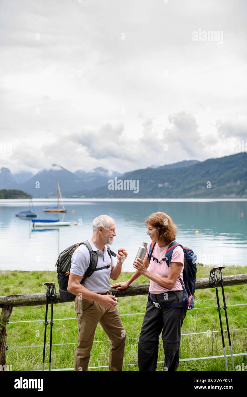 Active elderly couple hiking together in mountains. Drinking coffee and having healthy snack, to ...